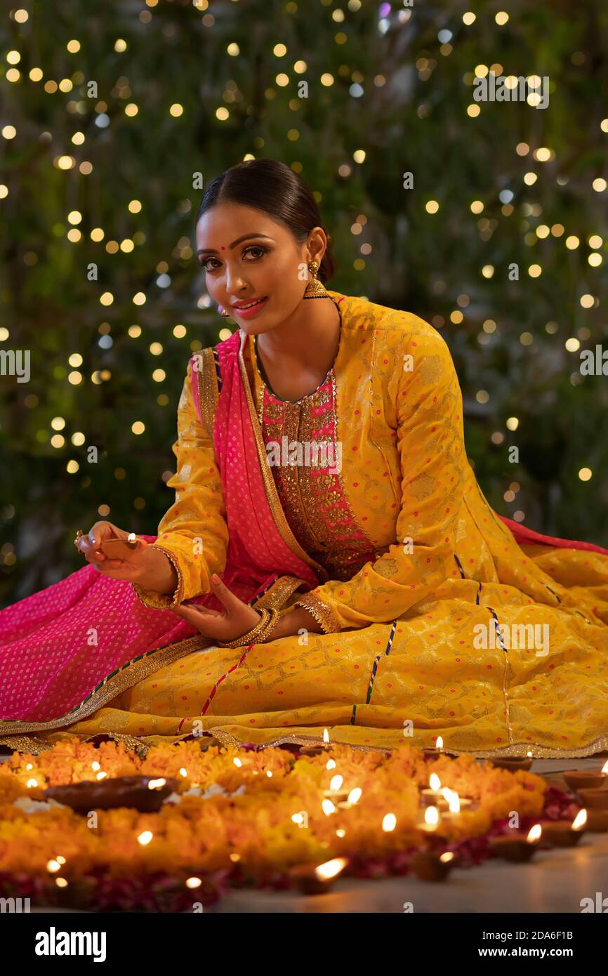 Beautiful woman decorating Rangoli with diya Stock Photo - Alamy