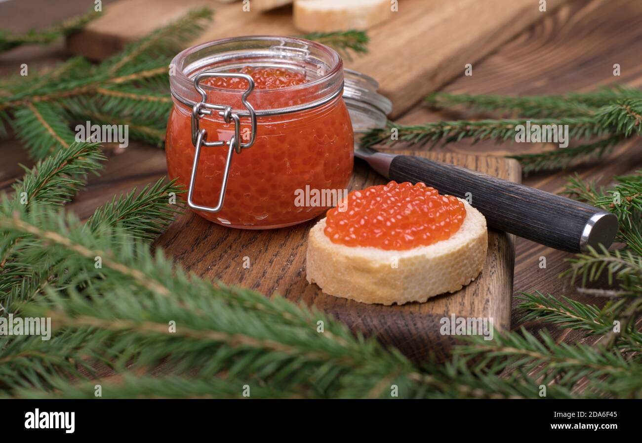 Red caviar in a glass jar on a brown wooden background with a Christmas ...