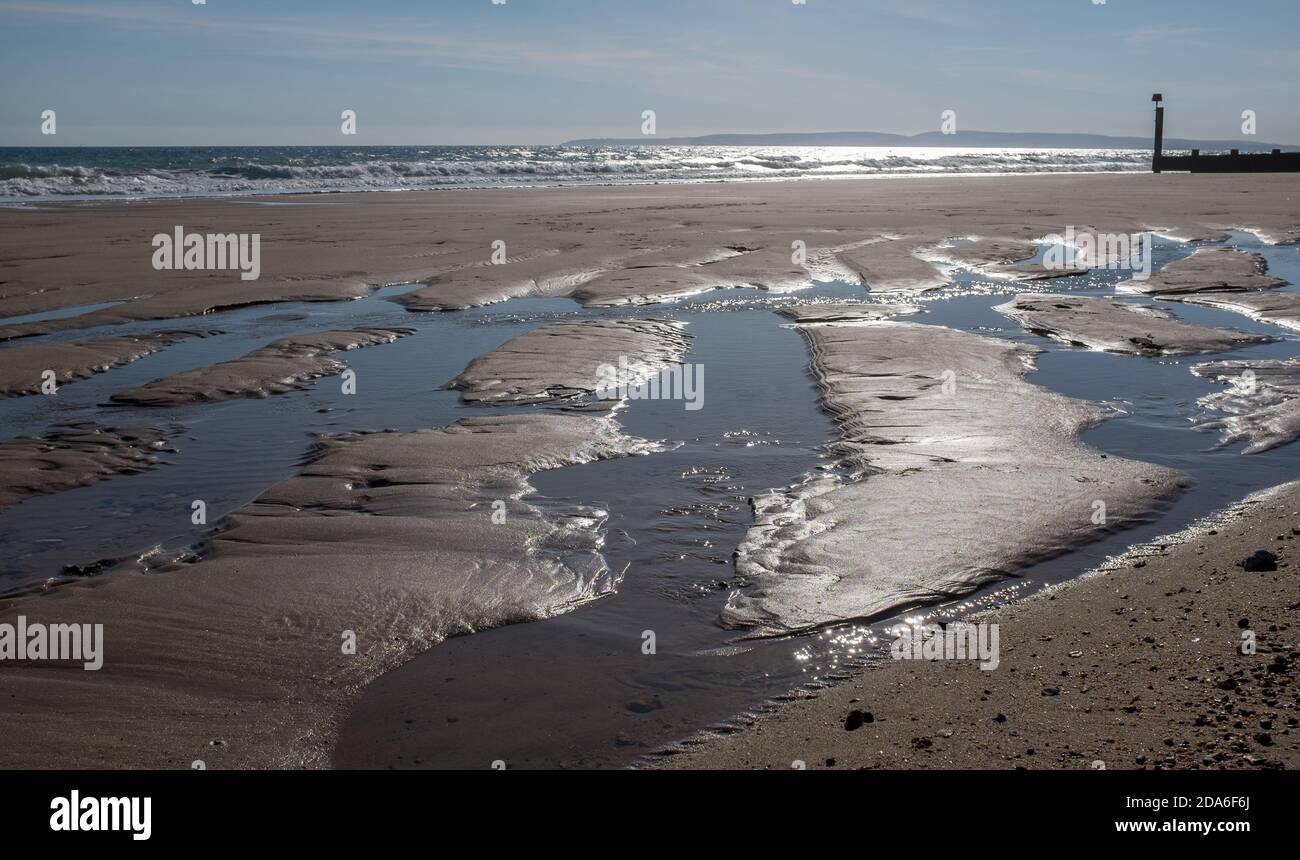 Pools of water and wet sand at low tide on the beach at Boscombe which ...