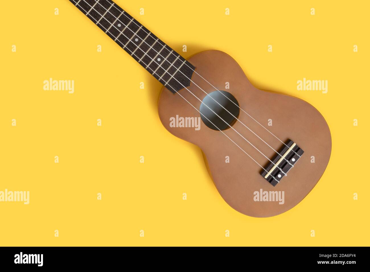 Flat lay of ukulele on a bright yellow background. Musical equipment ...