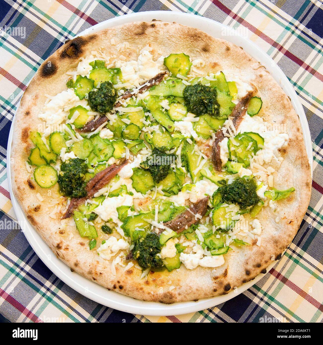 a real italian vegetable pizza in a dish, courgettes, anchovies and ...
