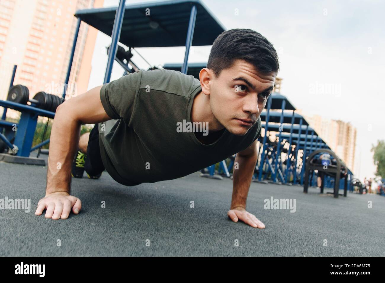 A young man does push-ups on the street on a specialized sports ground ...