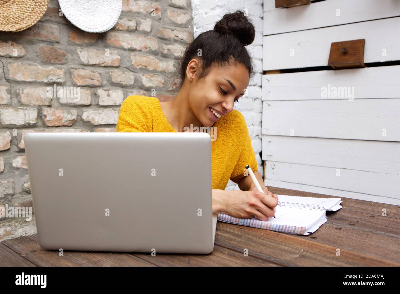Portrait of beautiful african woman writing a book on cafe table with ...