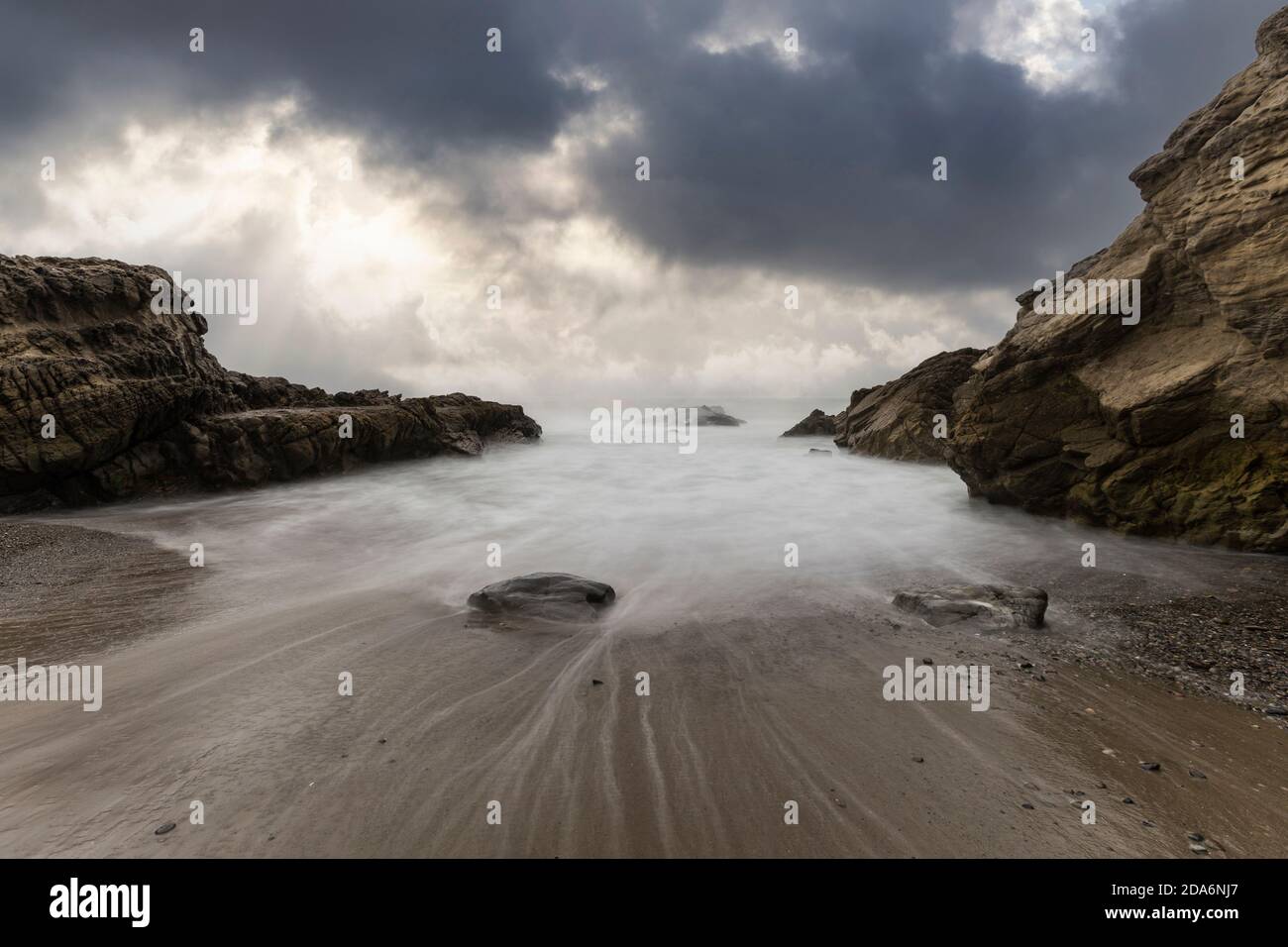 Rocky cove with motion blurred water and stormy sky at Leo Carrillo ...