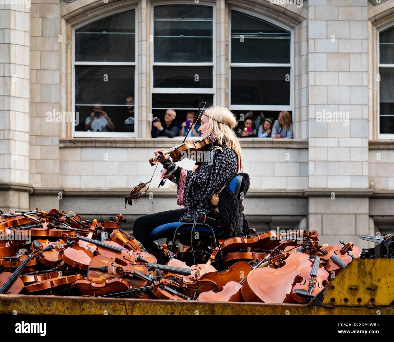 Violinist in a float featuring a skip full of stringed instruments ...