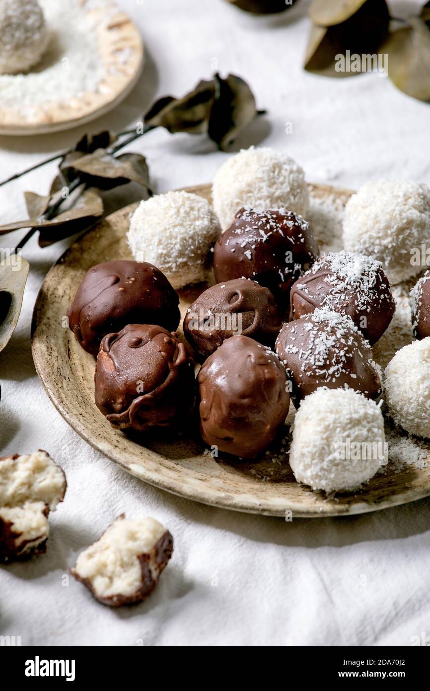 Raw vegan coconut chocolate candy balls over white with eucalyptus ...