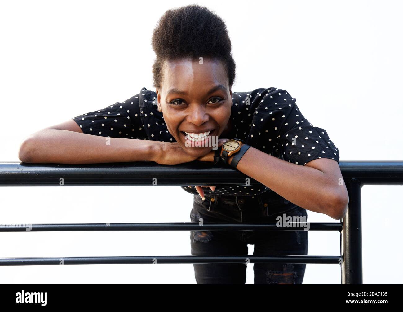 Close up portrait of cheerful young african woman leaning on railing ...