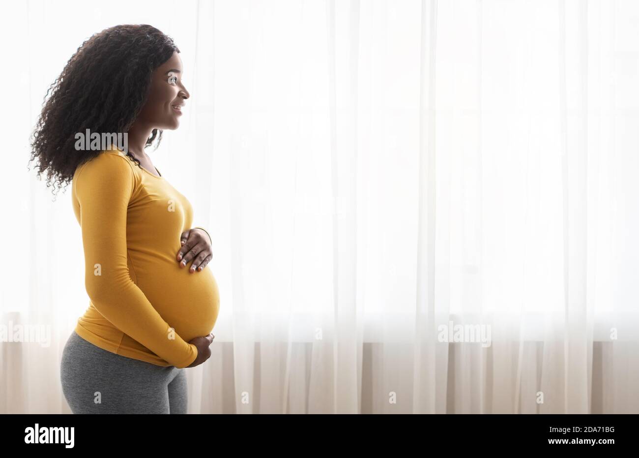 Black expecting lady looking at copy space Stock Photo - Alamy