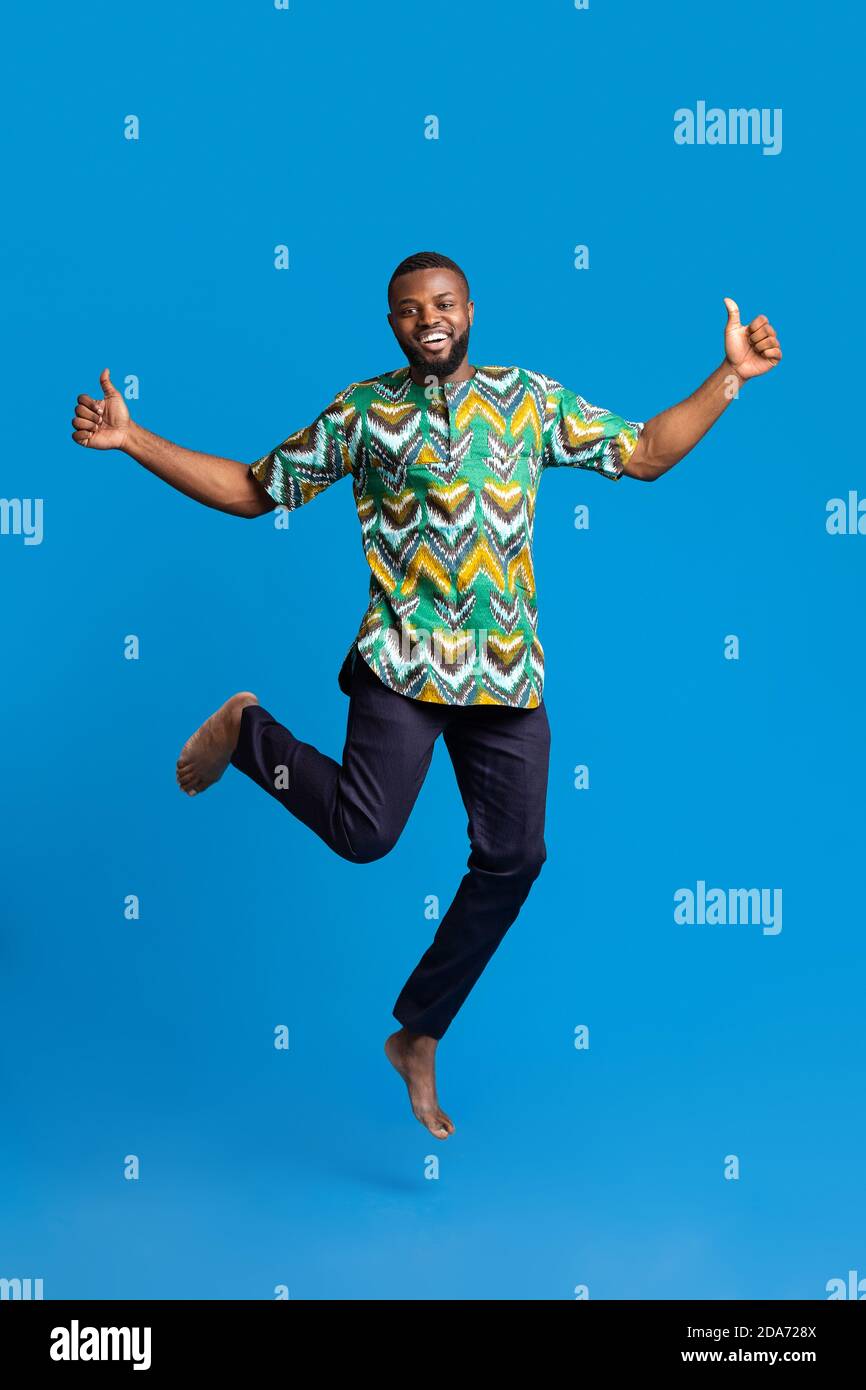 Positive black man jumping up over blue Stock Photo - Alamy