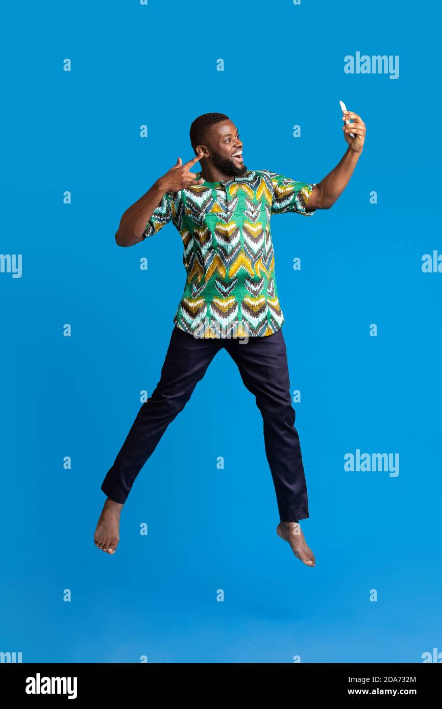 Happy black guy in african costume taking selfie Stock Photo - Alamy