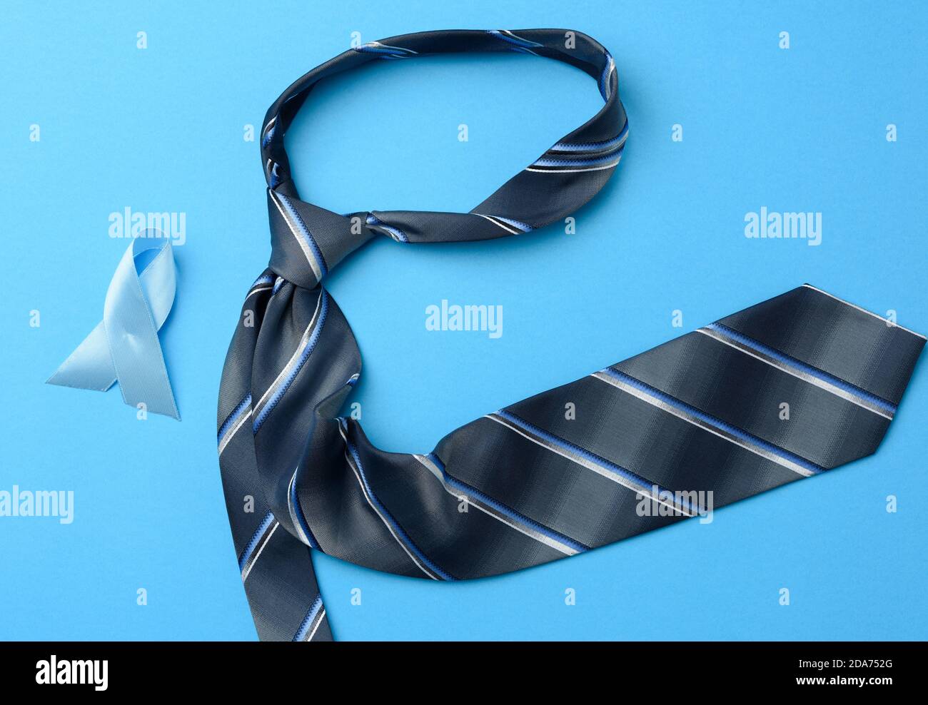 silk blue mens tie and ribbon folded in a loop on blue background ...