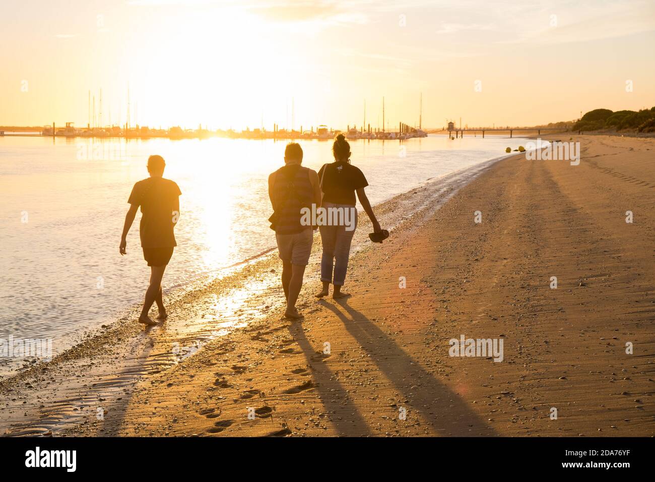 Group of friends walking at the beach during sunset Stock Photo - Alamy