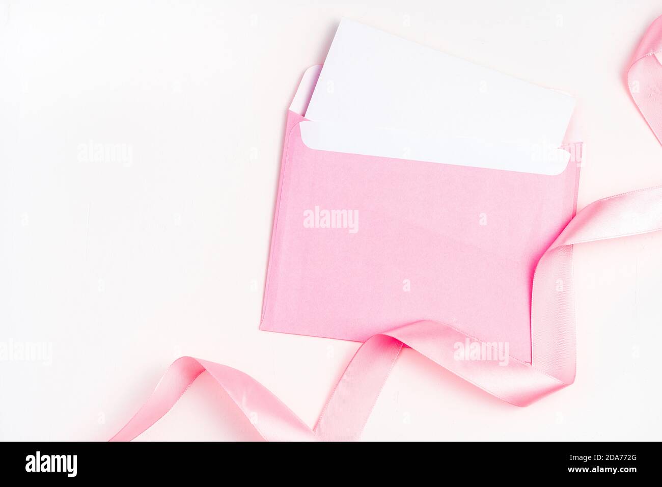 Pink envelope and satin ribbon on a light background Stock Photo - Alamy