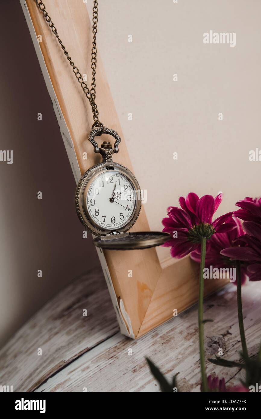 old round vintage watch on a chain among flowers in the interior Stock ...