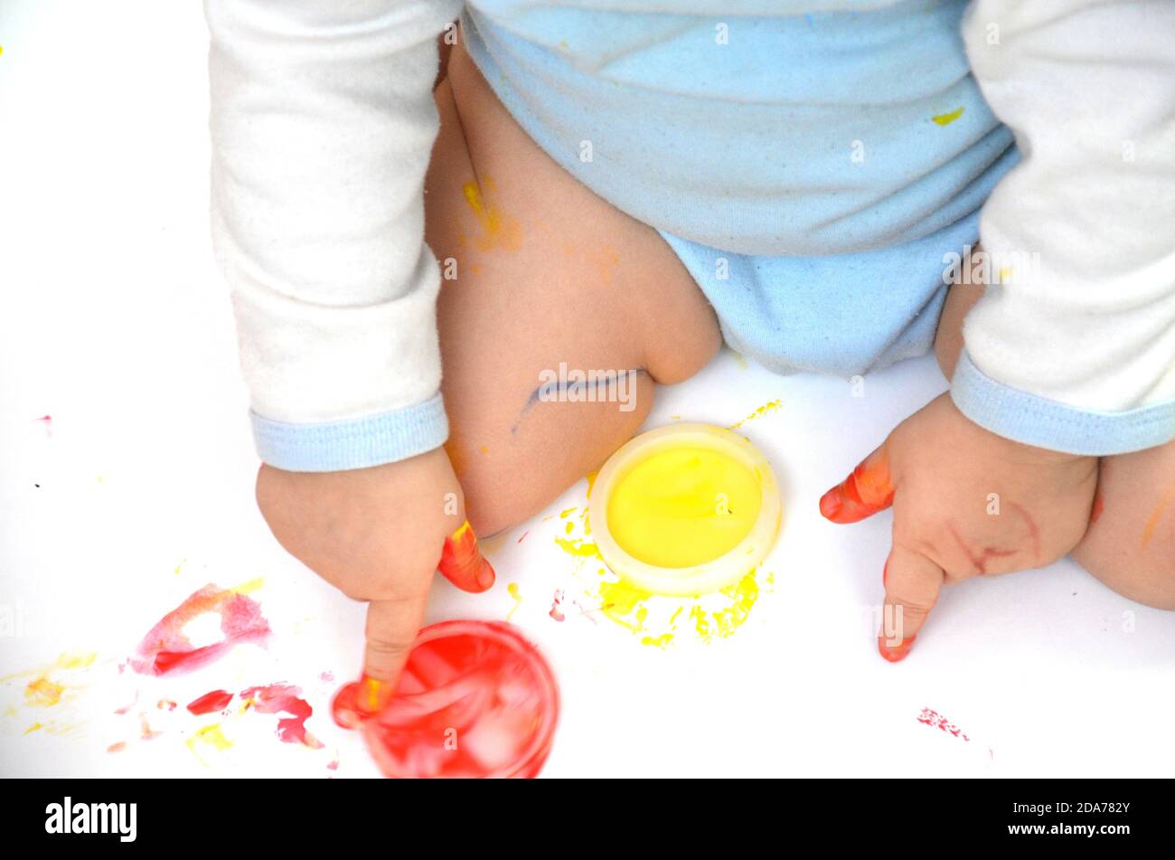 happy baby child draws with colored paints hands, fingers and palms are ...