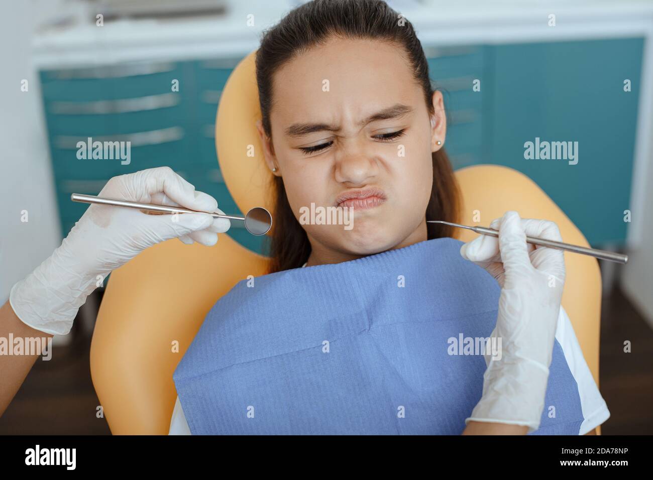 Portrait of small hispanic kid in chair looking at hands of doctor in ...