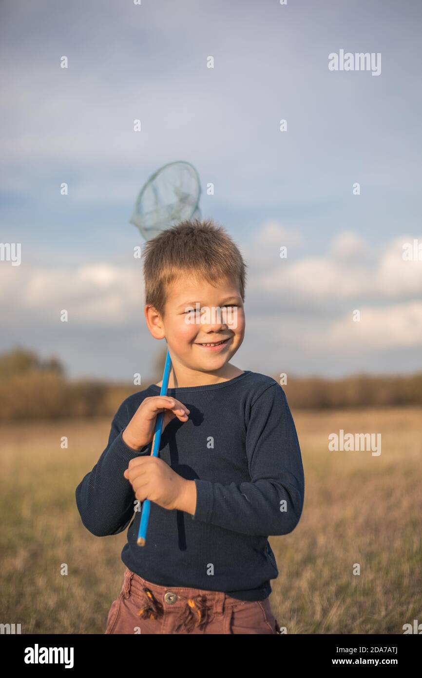 Young boy with butterfly net walking meadow. Child playing catching ...