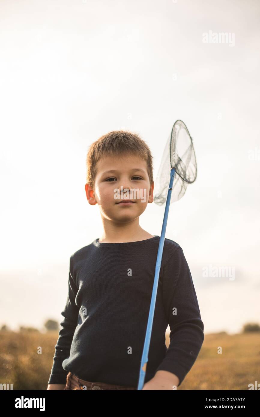 Young boy with butterfly net walking meadow. Child playing catching ...