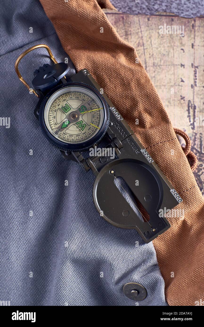 Top view closeup of a compass placed on a colorful fabric next to an ...