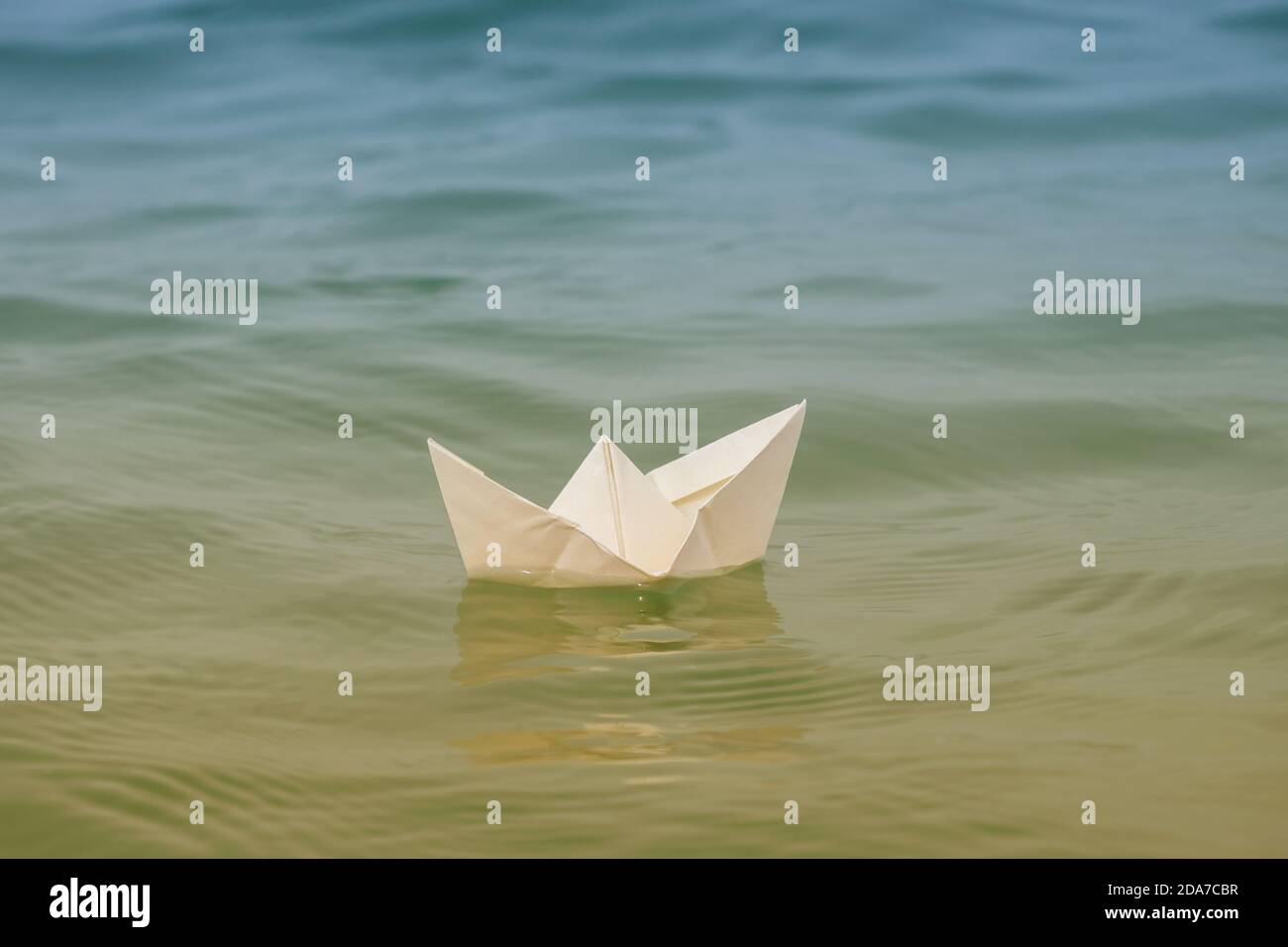 handmade paper boat sailing on water causing waves and ripples Stock ...