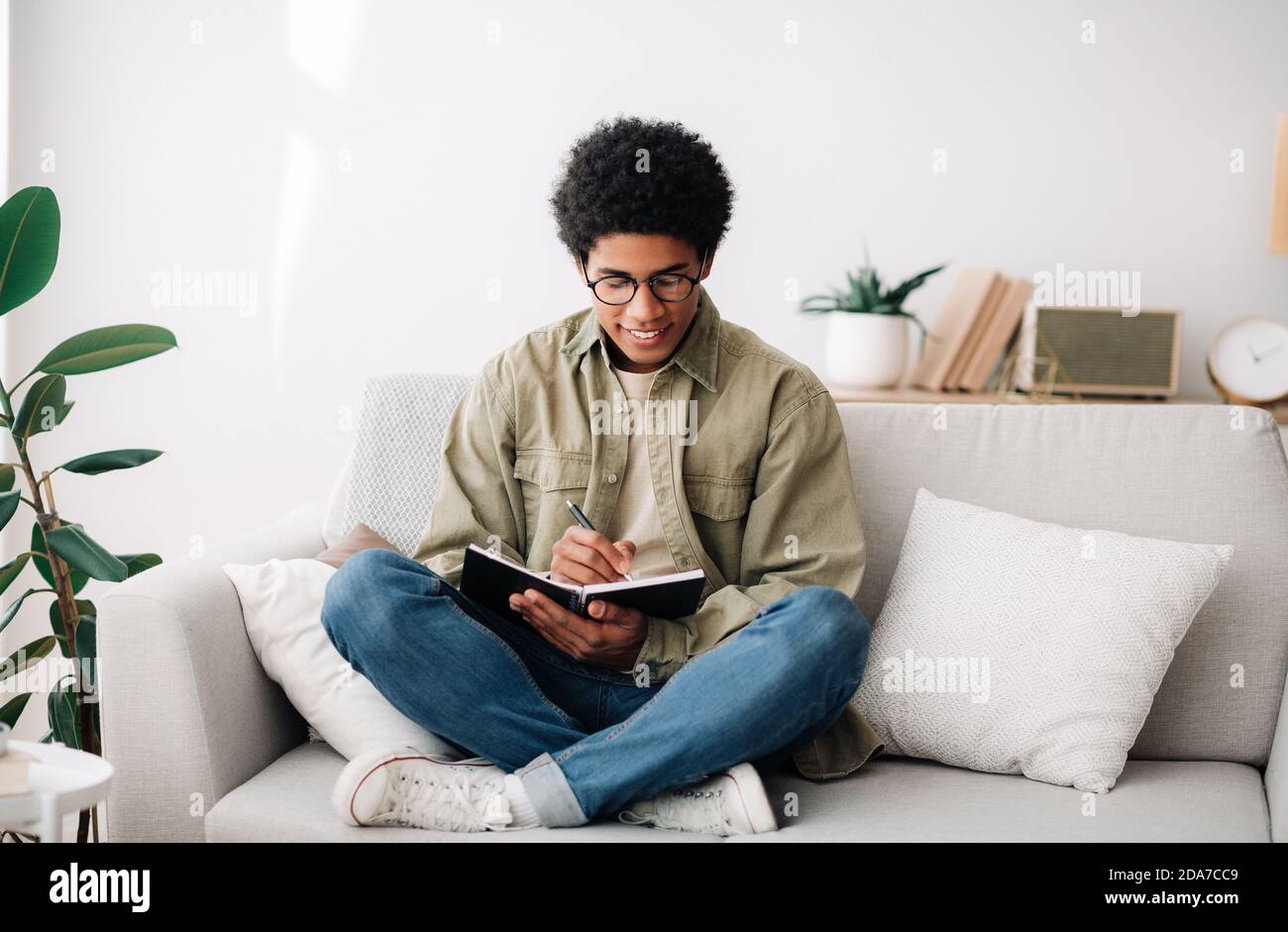 Focused African American student taking notes in copybook, working on ...
