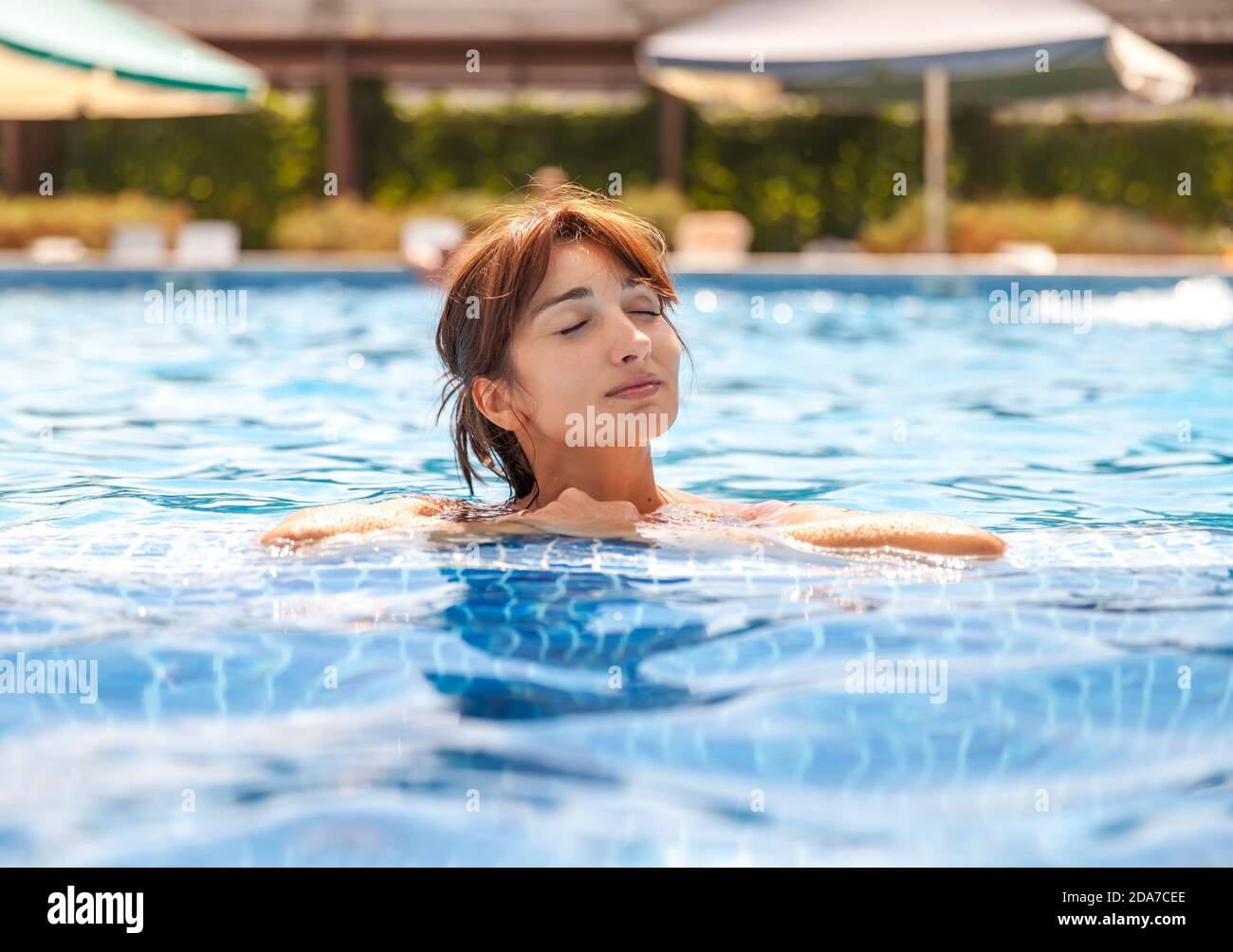 Portrait of a young woman with closed eyes relaxing in a swimming pool ...