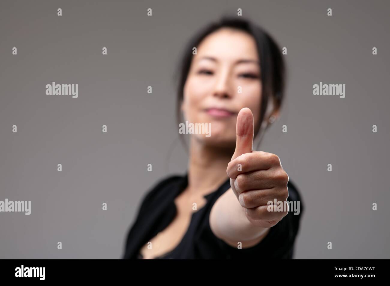 Elated triumphant Asian woman giving a thumbs up gesture of success and ...