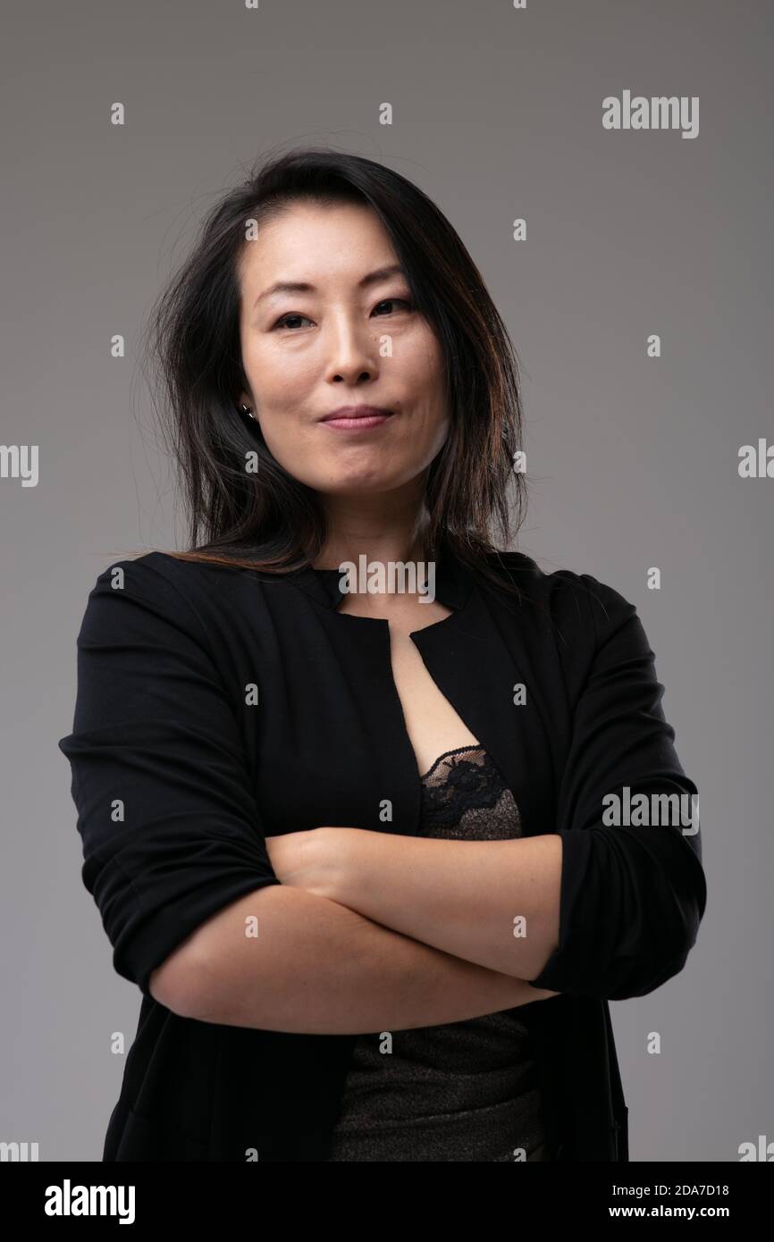 Confident professional Asian woman standing thinking with folded arms ...