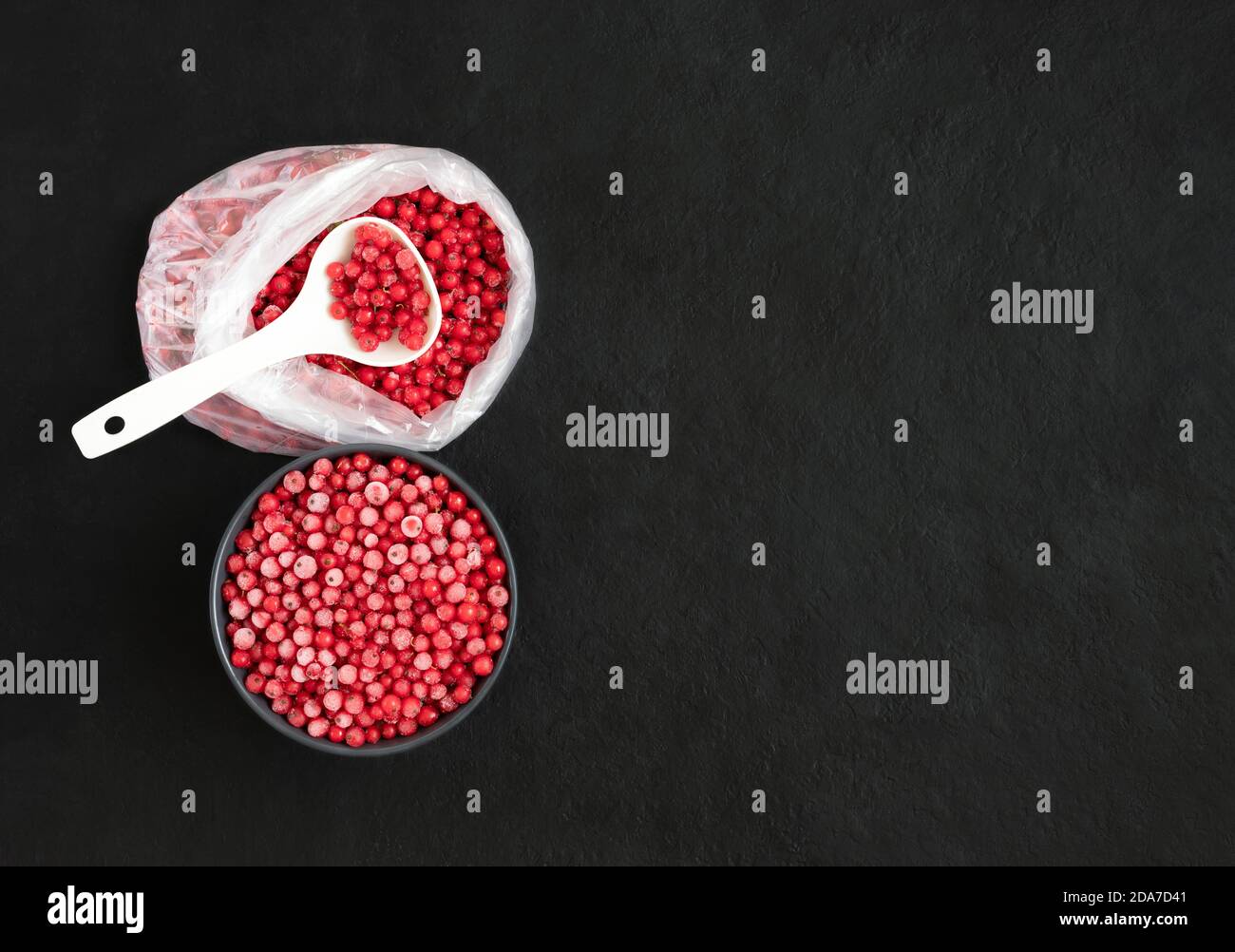 Frozen red currant on a black background. Red berries in a bowl and bag ...