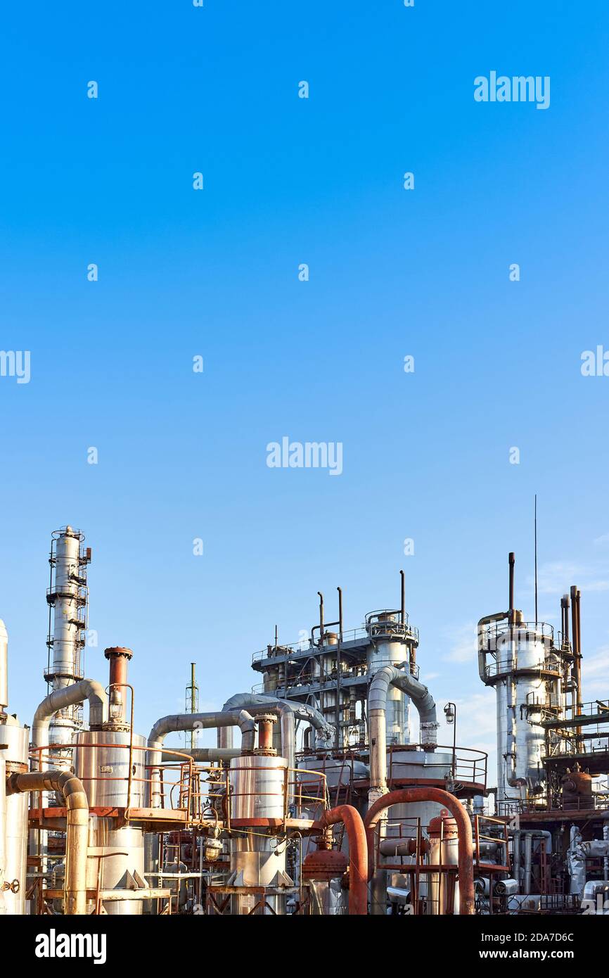 Old distillation column towers and reactors under blue evening sky ...