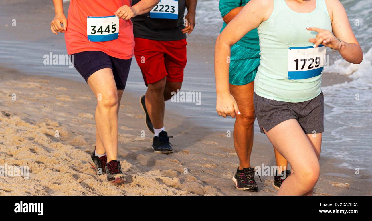 Four people running together at the edge of the beach close to the ...