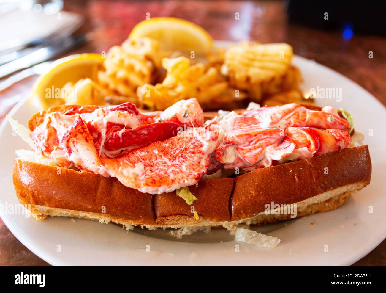 A fresh lobster roll served with waffle fries in a restaurant in ...