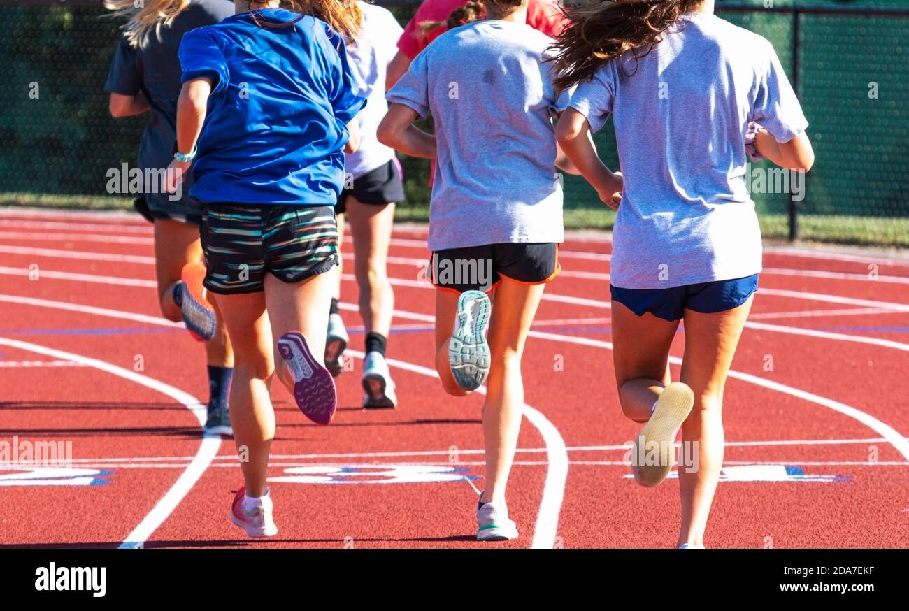 Rear view of a group of high school girls running on a track during ...