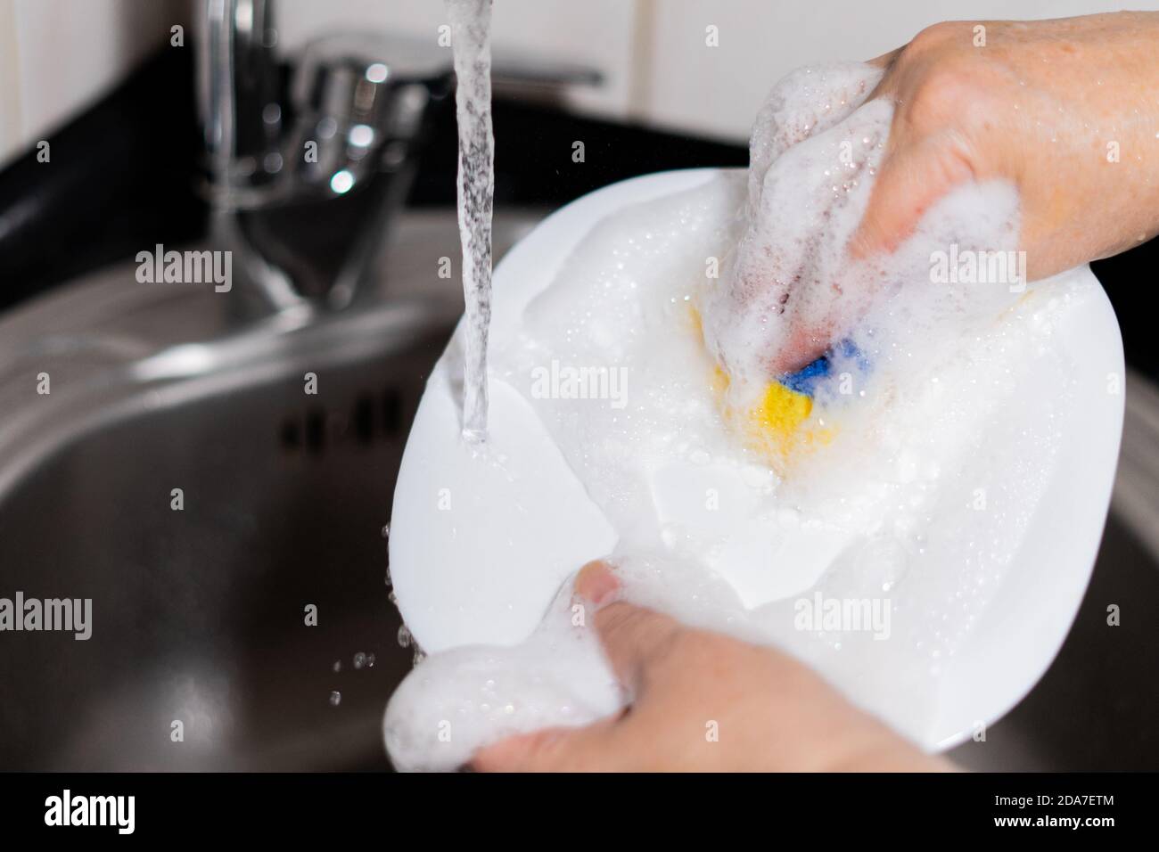 Girl washes dishes in the kitchen, wash a white plate Stock Photo - Alamy