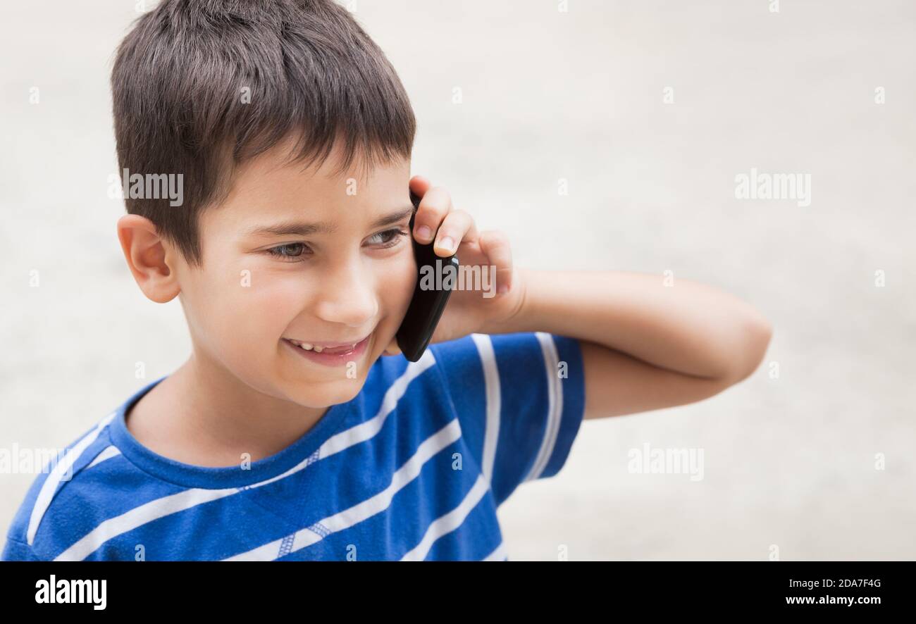 Happy little boy talking on the phone with his parents on light ...