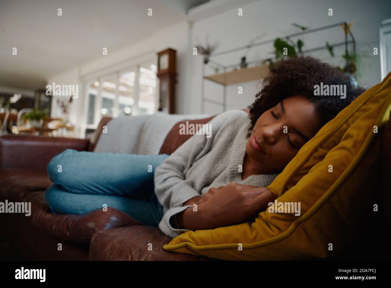 Tired young woman lying on coz couch taking a nap while daydreaming in ...