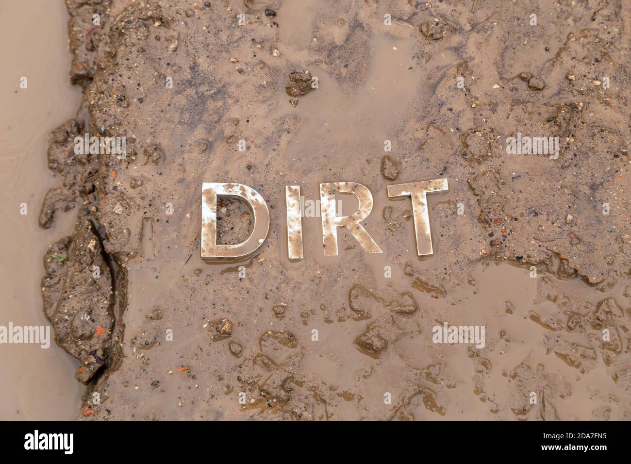 the word mud imprinted in wet dirt road surface - close-up with ...