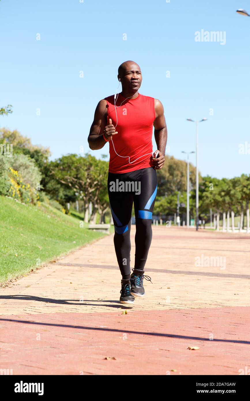 Full length portrait of fit exercising man running outside at the park ...