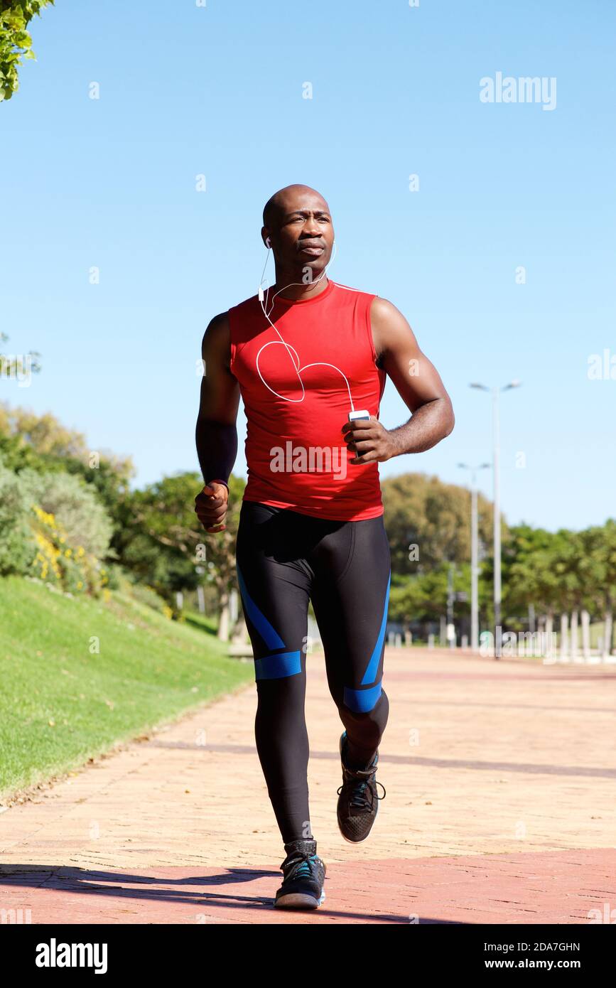 Full body portrait of fit young african man running outdoors at the ...