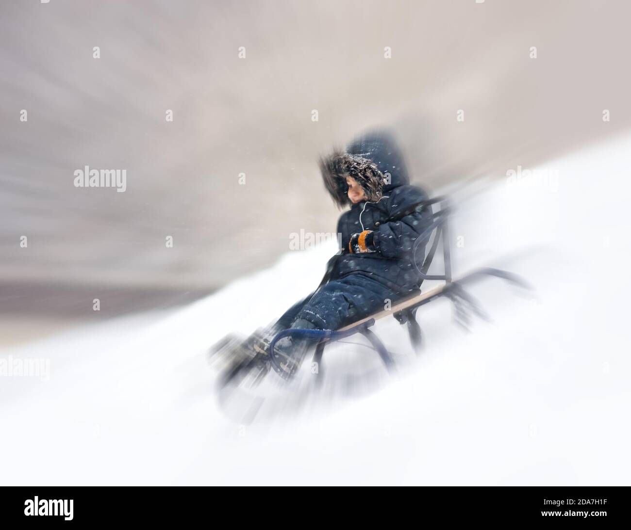 Young boy on sledge sliding fast down snowy hill with motion blur Stock ...