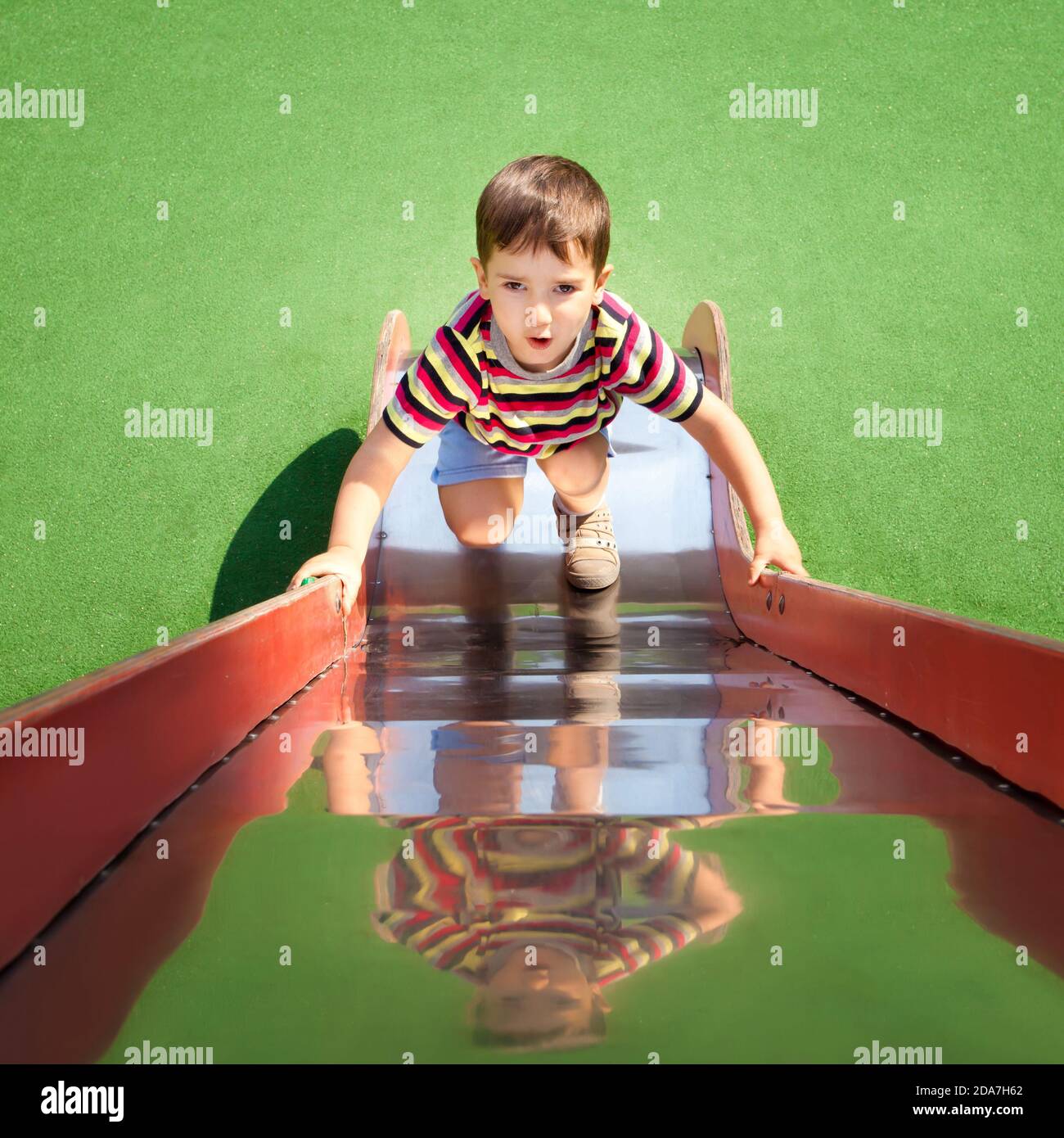 Cute young boy climbing up a slide on playground Stock Photo - Alamy