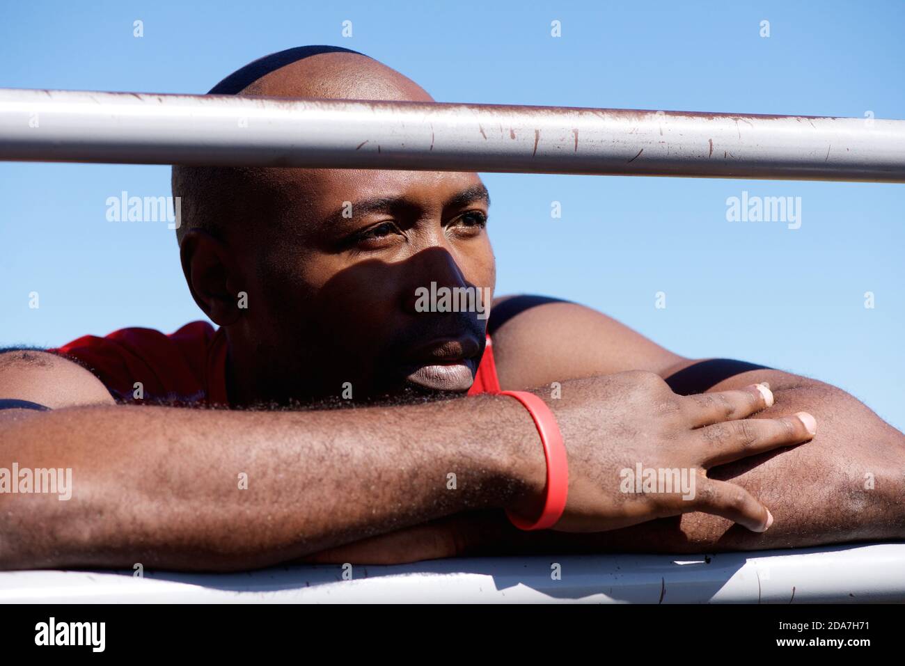 Close up portrait of fit young black man leaning on railing outdoors ...