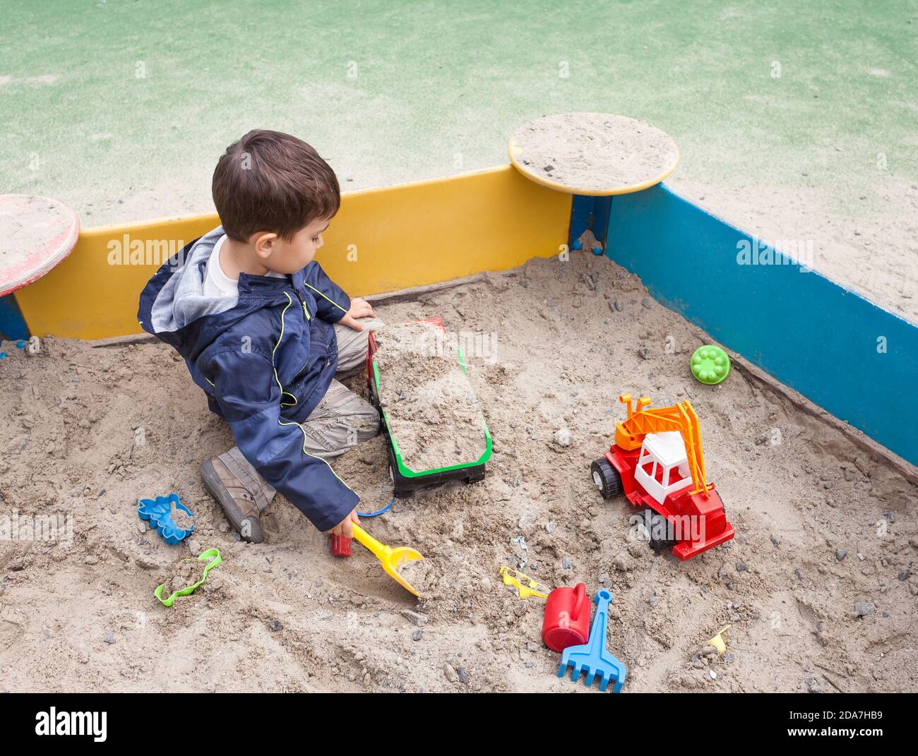 Cute boy in jacket playing in sandbox with a lot of sand toys Stock ...
