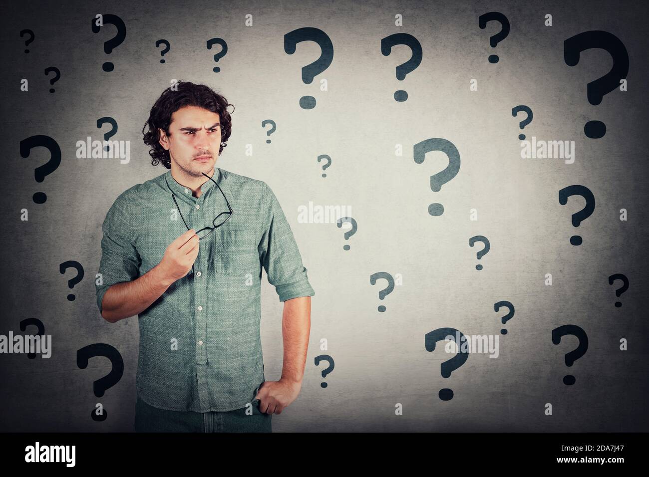 Puzzled man holds eyeglasses in his hand, thoughtful gesture, looking ...