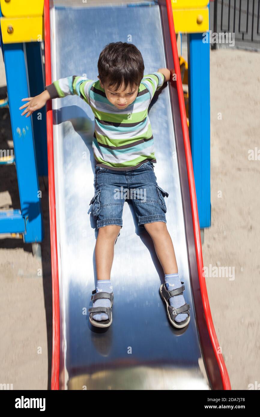 Cute boy playing on slide Stock Photo - Alamy