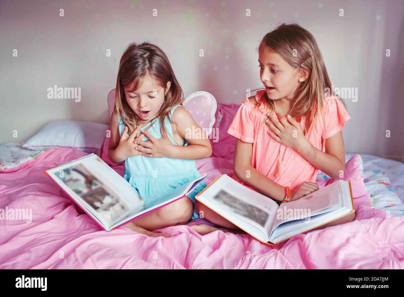 Surprised scared Caucasian sisters girls reading books in bedroom. Home ...