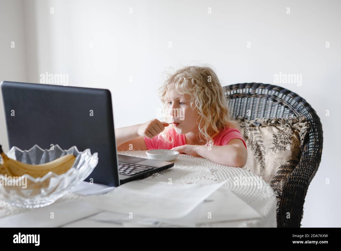Young girl eating food and watching cartoons on laptop. Child with ...