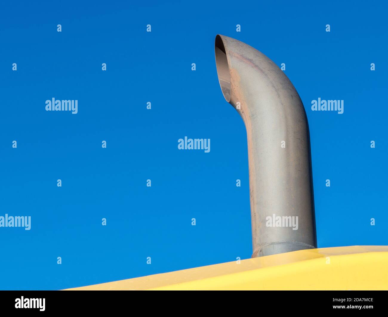 weathered chrome exhaust stack on a bulldozer under blue sky with copy ...