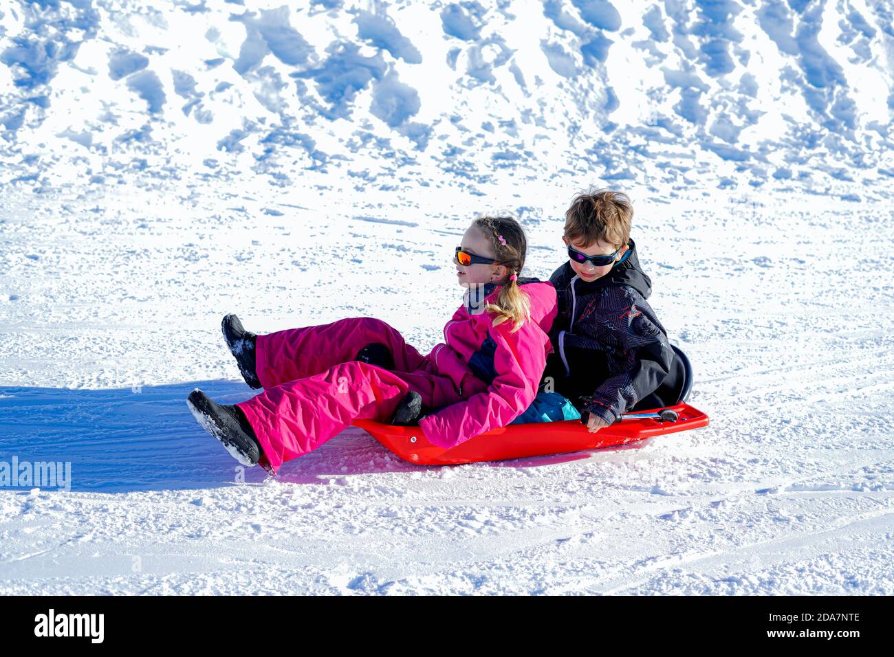 Two joyful kids sledding down the hills on a winter day. Brother and ...