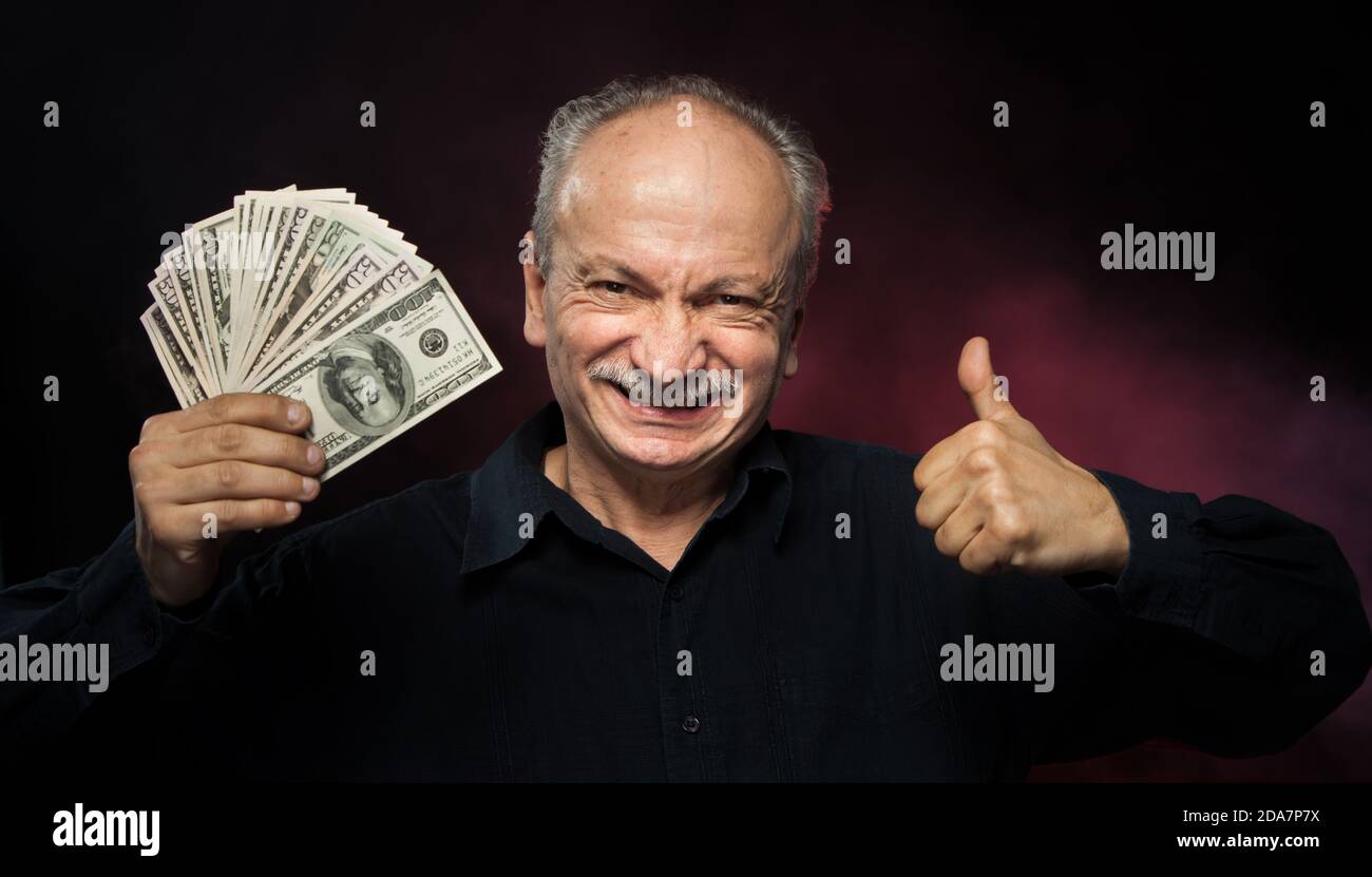 Senior gentleman holding a stack of money. Portrait of an excited old ...